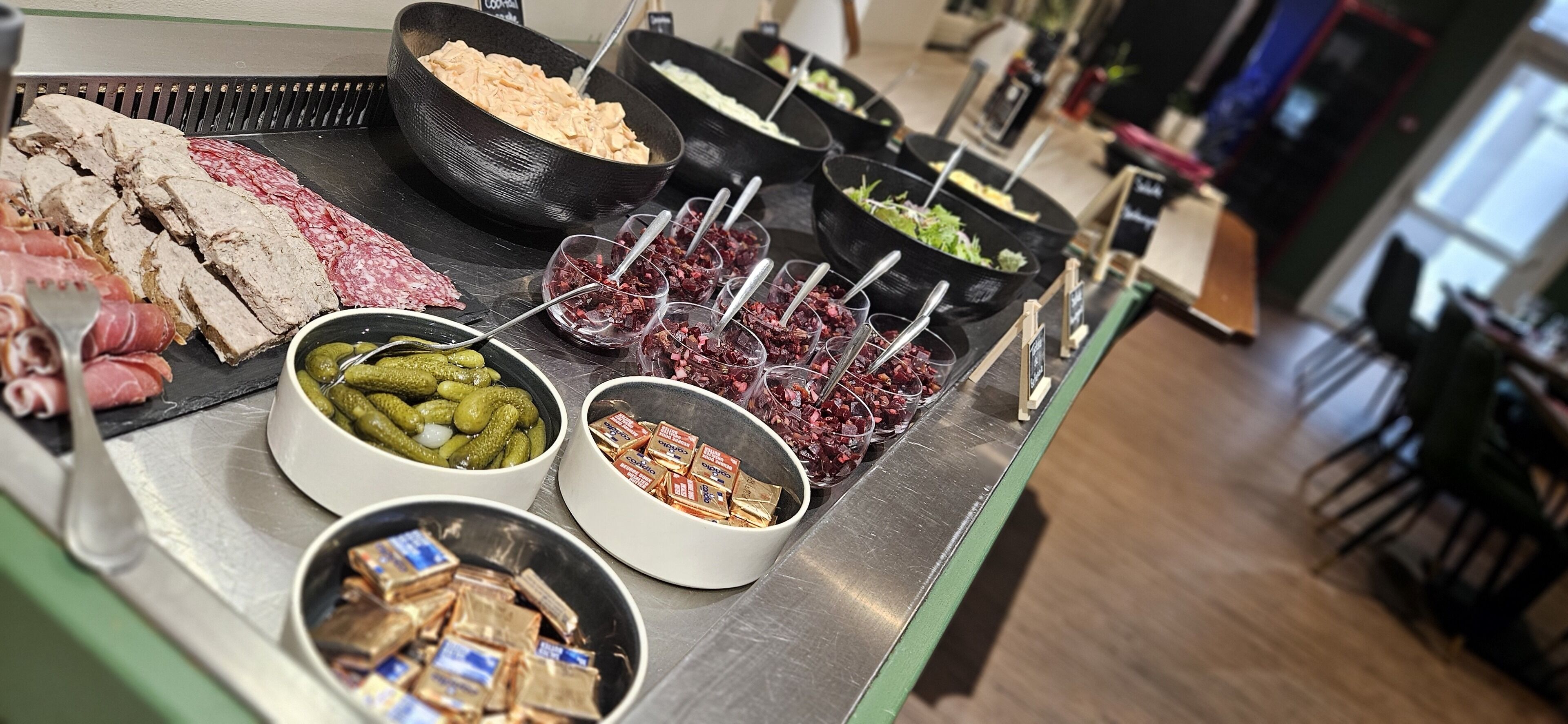 Buffet com diversos alimentos, incluindo carnes, picles e acompanhamentos.