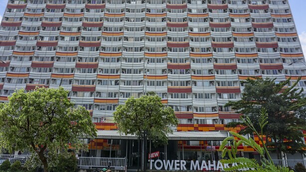Um edifício alto com várias varandas e um andar térreo comercial.
