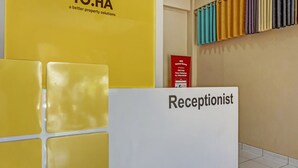 Uma área de recepção com uma placa indicando 'Receptionist' e uma placa para 'TO.HA a better property solutions'.