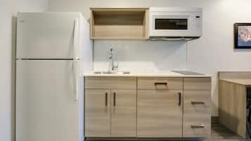 Um frigorífico/congelador grande, um micro-ondas, uma placa de cozinha