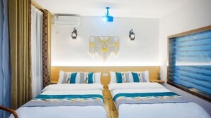 Quarto de hotel com duas camas, uma luminária no teto, arandelas na parede, janela com persianas e um ar condicionado.