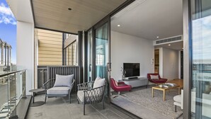 Uma sala de estar moderna com televisão, uma cadeira vermelha, uma cadeira cinza e uma mesa pequena.