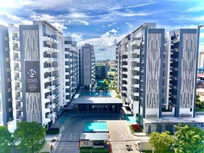 Um hotel-apartamento com serviços modernos, com vários edifícios altos, área de piscina central e pátio ajardinado.