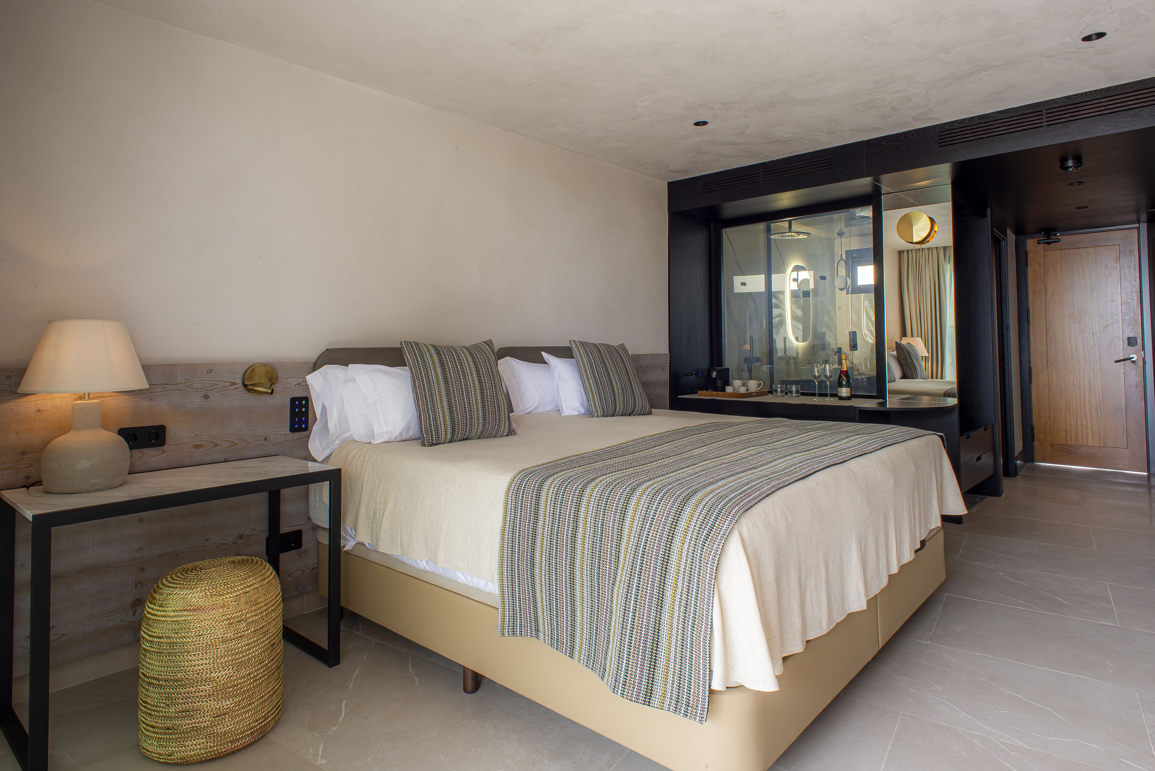 Quarto moderno com cama grande, mesas de cabeceira, espelho e guarda-roupa.