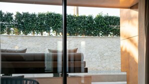 Quarto moderno com parede de pedra, sofá e divisória de vidro.