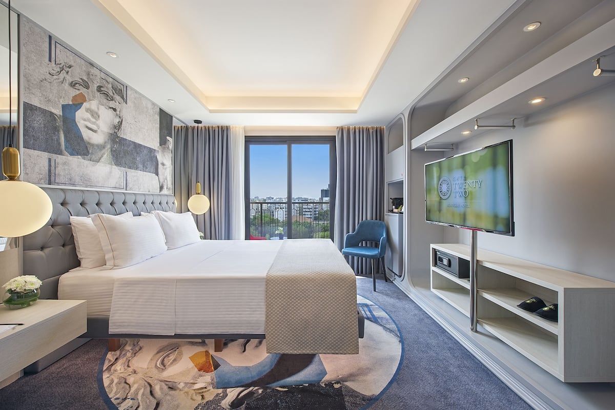 Quarto de hotel moderno com cama grande, televisão de tela plana, escrivaninha e vista para a cidade.