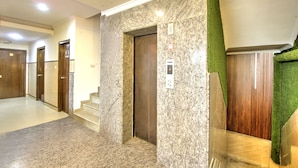 Um elevador com parede de mármore, parede de grama sintética verde e painel de madeira.