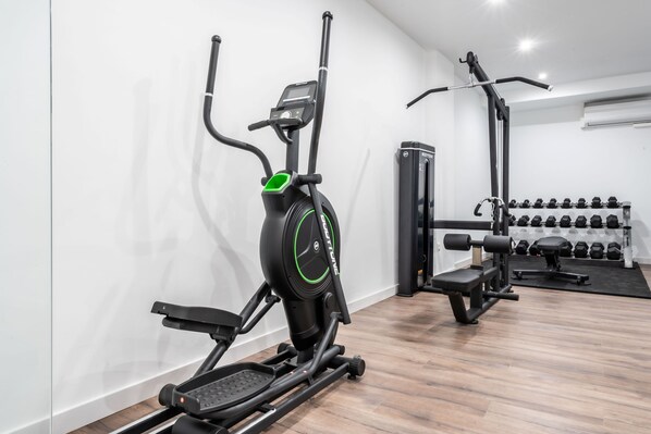 Uma academia moderna com equipamentos de cardio, aparelhos de musculação e halteres organizadamente dispostos.