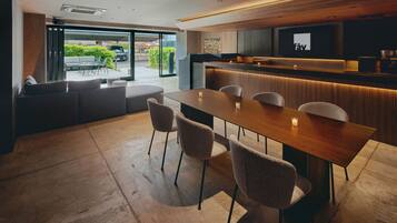 Um hall de hotel moderno com uma receção em madeira, uma televisão de ecrã plano grande e uma área de estar com sofás e cadeiras.