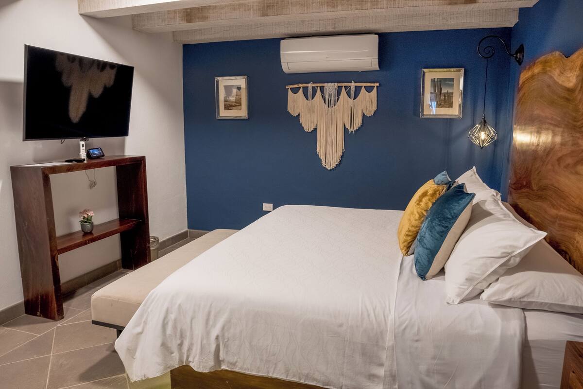 Quarto com uma cama, televisão, prateleira e decorações nas paredes.