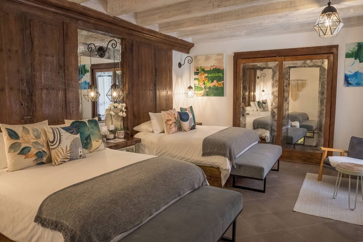 Quarto com duas camas, uma cadeira e um espelho.