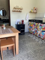 Uma cozinha com uma mesa de jantar, um armário preto, toalhas de cozinha coloridas e piso em azulejos.