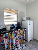 Cozinha equipada com frigorífico, micro-ondas e janela com persianas.