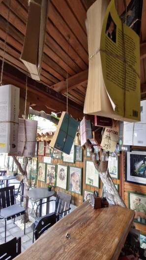 Teto de madeira rústica com livros pendurados e quadros nas paredes.
