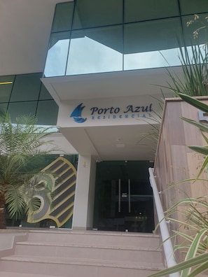 Um edifício moderno com uma placa indicando 'Porto Azul Residencial' e uma escadaria que leva à entrada.