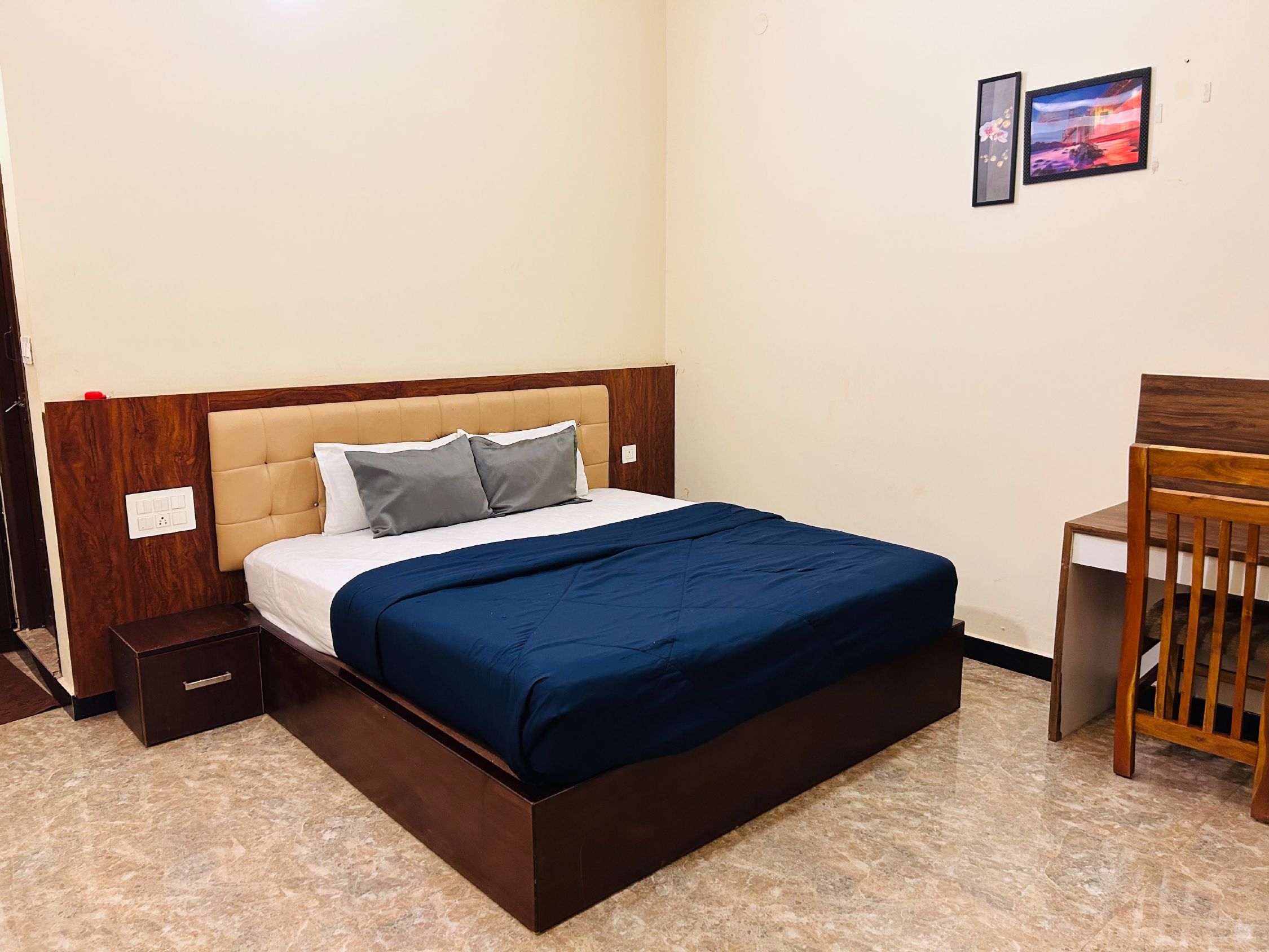 Quarto de hotel com cama, mesa de cabeceira e escrivaninha.