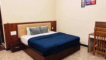 Quarto de hotel com cama, mesa de cabeceira e escrivaninha.