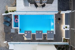 Piscina no terraço com interior azul, rodeada por espreguiçadeiras e uma mesa.