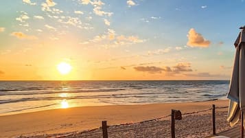 Na praia, espreguiçadeiras, guarda-sóis de praia, toalhas de praia