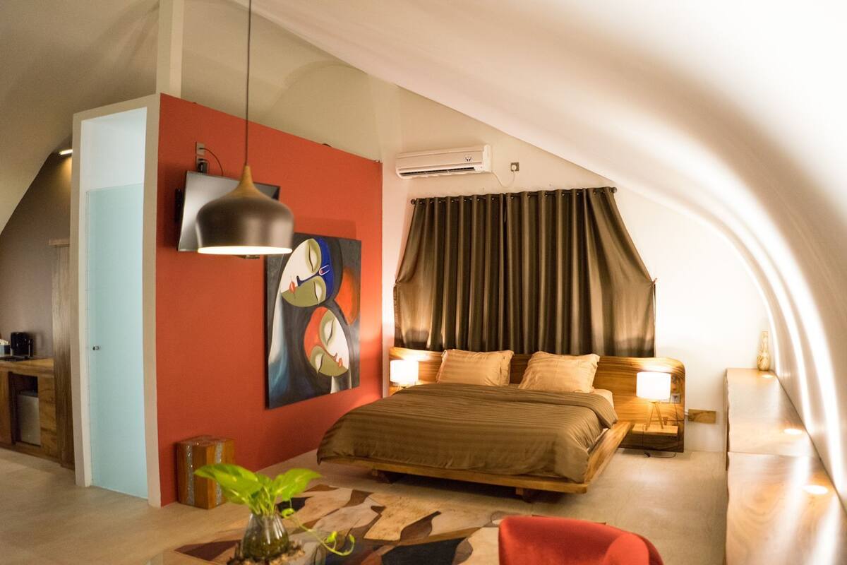 Quarto com cama, pintura, planta e ar condicionado.