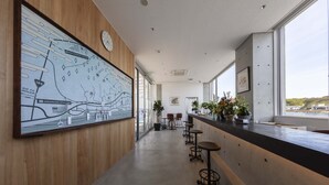 Um interior moderno com um mapa grande na parede, área de bar com banquetas e janelas amplas com vista.