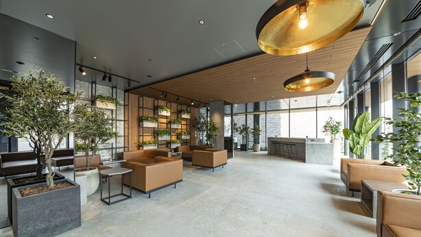 Um hall amplo com mobiliário moderno, grandes janelas e plantas em vasos.