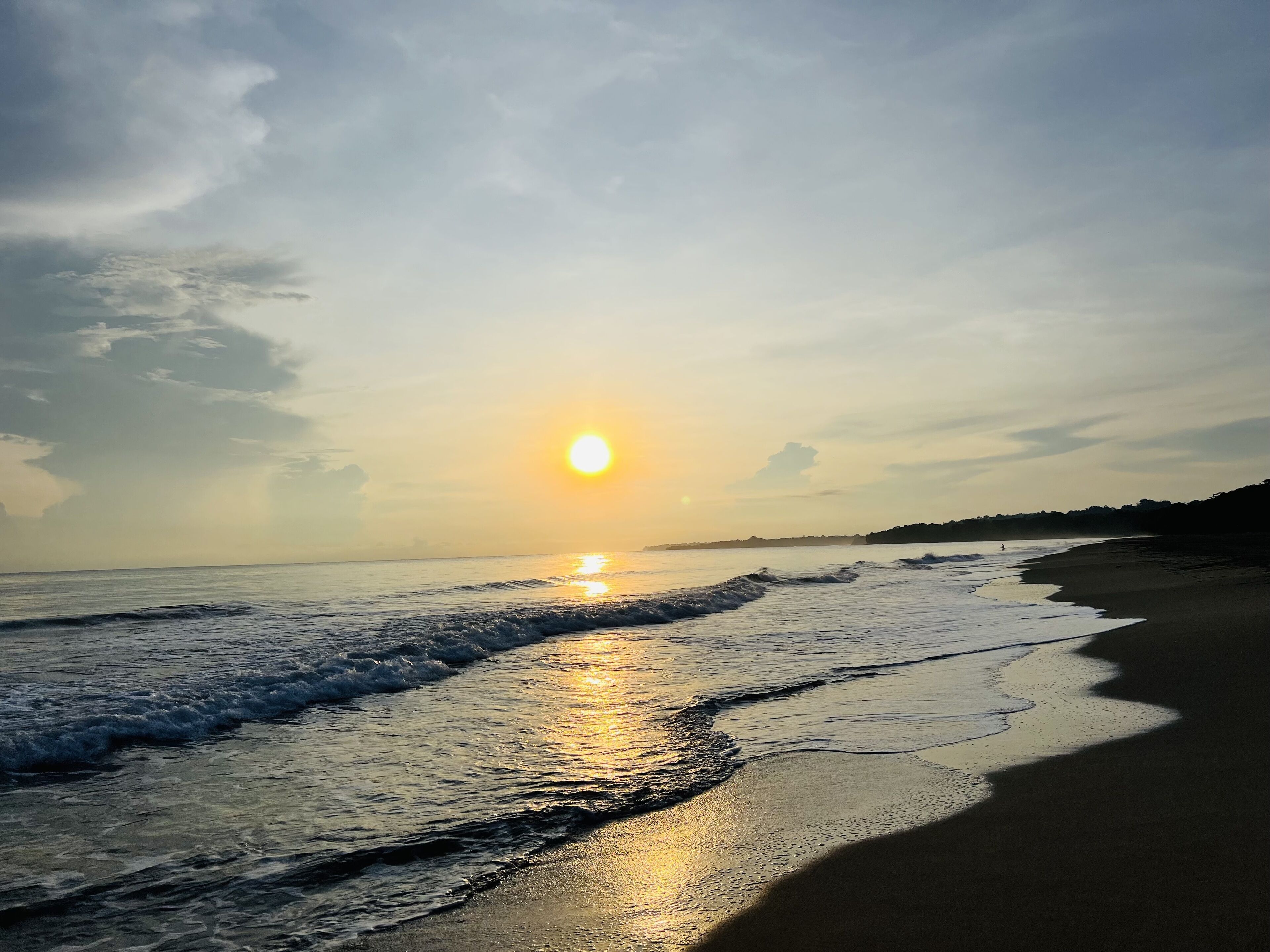 Uma praia com ondas e um pôr do sol.