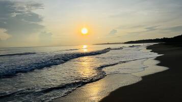 Uma praia com ondas e um pôr do sol.