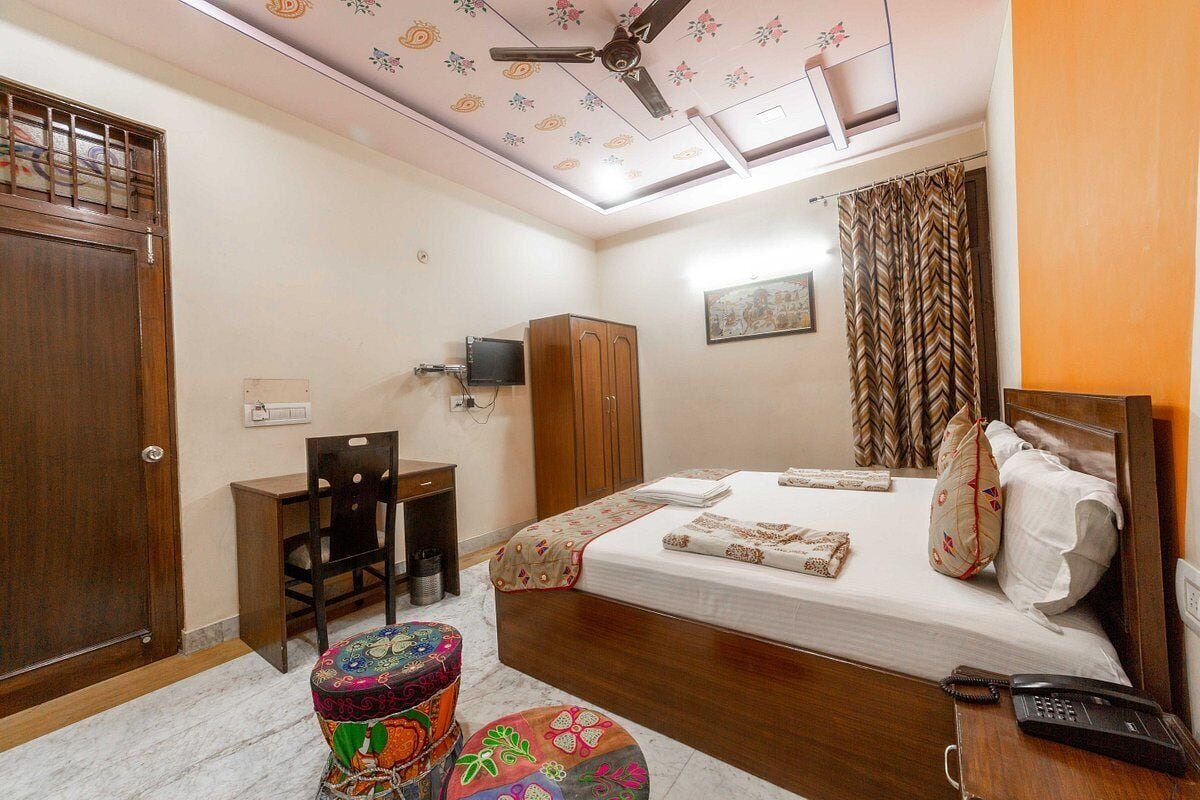 Quarto com cama, escrivaninha, cadeira, guarda-roupa e ventoinha no teto.