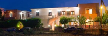 Um edifício moderno de dois andares com telhado plano, várias janelas e uma varanda.