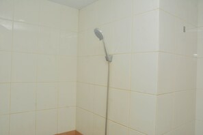 Chuveiro com chuveiro manual em banheiro revestido com azulejos.