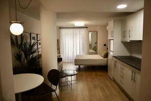 Uma cozinha compacta com área de refeições, uma cama e uma pequena mesa com cadeiras.