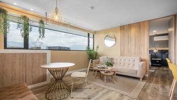 Uma sala de estar moderna com um sofá, uma mesa de jantar redonda e um lustre.