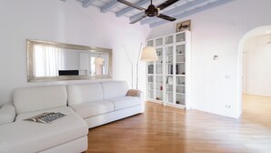 Uma sala de estar ampla com um sofá branco, um ventilador de teto e um armário grande com portas de vidro.