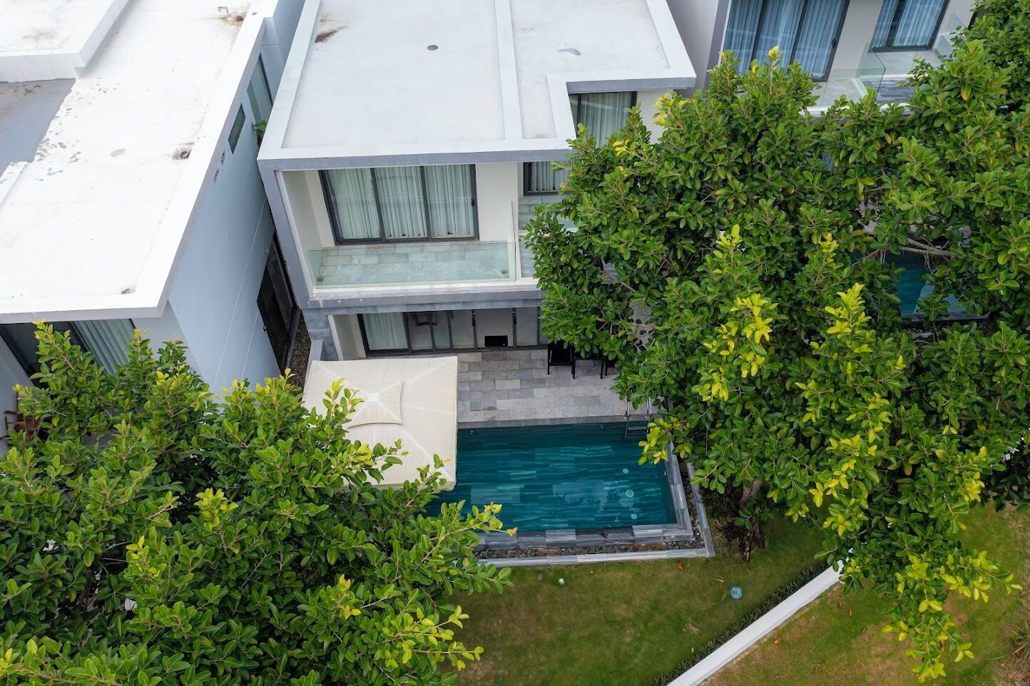 Um edifício moderno com piscina, rodeado por vegetação exuberante.