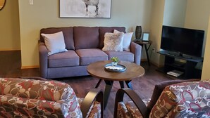 Uma sala de estar com sofá, mesa de centro e televisão.