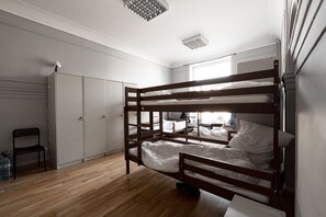 Quarto com beliche, piso de madeira, guarda-roupa e uma cadeira.