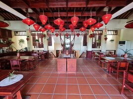 Um restaurante em estilo tradicional, com mobiliário de madeira, lanternas vermelhas e pisos azulejados.