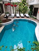 Piscina com borda revestida, rodeada por espreguiçadeiras e uma escadaria que dá acesso a um andar superior.