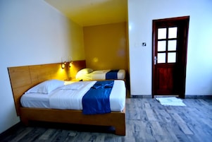 Um quarto com uma cama de madeira, uma mesa de cabeceira e uma porta.