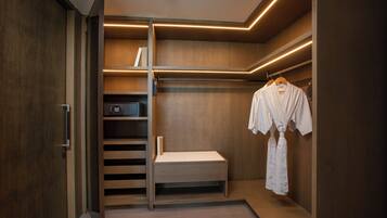 Um closet amplo com prateleiras de madeira, um banco e robes pendurados.