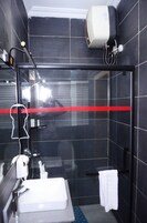 Um banheiro moderno com chuveiro em vidro, pia branca e porta-toalhas.