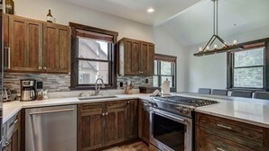 Uma cozinha moderna com armários de madeira, eletrodomésticos de aço inoxidável e uma janela grande que oferece luz natural.