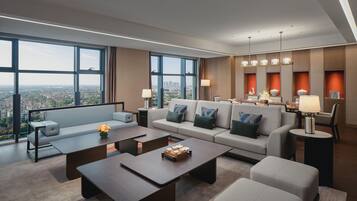 Quarto de hotel moderno com ampla vista da cidade, um conjunto de sofás, área de refeições e espaço bem iluminado.