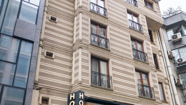 Um hotel chamado Dolce Vita Suite & Hotel com fachada moderna, grandes janelas e área de estar ao ar livre.