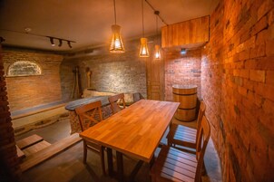 Uma área de jantar rústica com mesa e bancos de madeira, paredes de tijolo e luminárias pendentes.