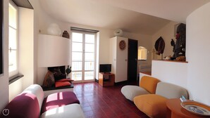 Uma sala de estar com sofá, poltronas, televisão e uma mesinha.