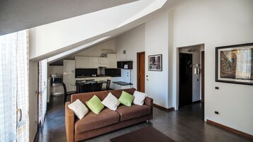 Uma sala de estar moderna com um sofá marrom, uma mesa de jantar e uma cozinha ao fundo.