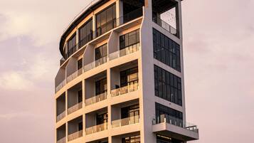 Um edifício de vários andares com varandas, grandes janelas e fachada curva.