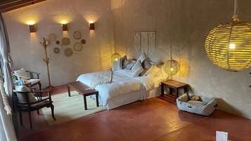 Um quarto aconchegante com cama, mesas de cabeceira, uma poltrona e um lustre.